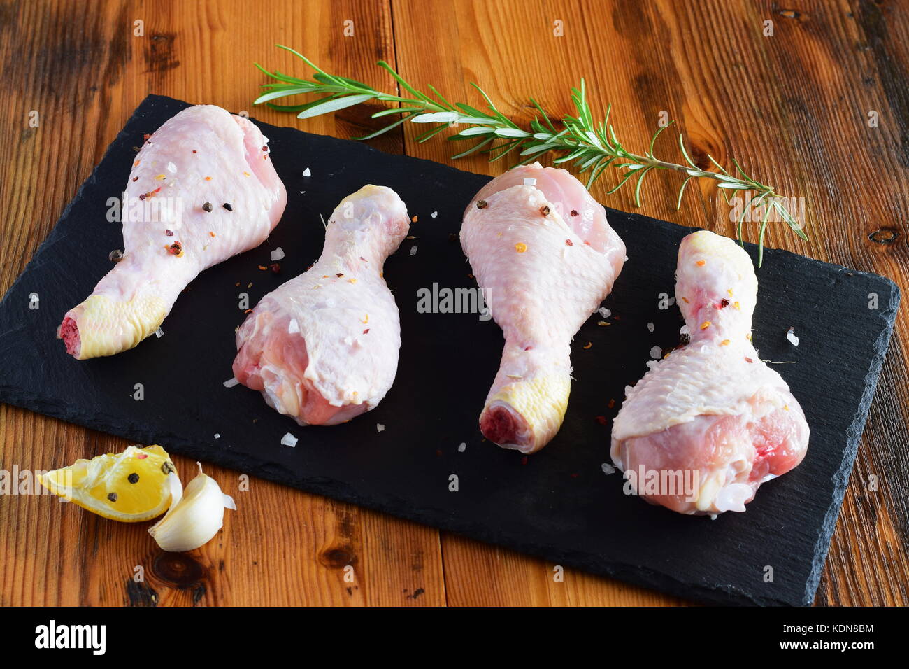 raw chicken legs on a black slate, wooden background Stock Photo - Alamy