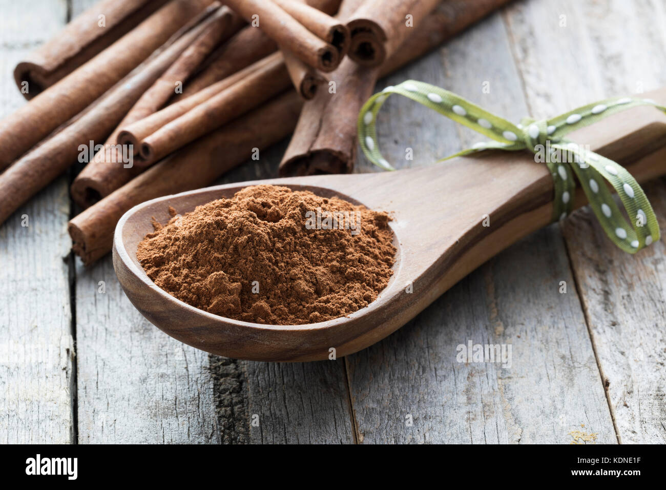 Close up of wooden spoon filled with ground cinnamon in front of ...