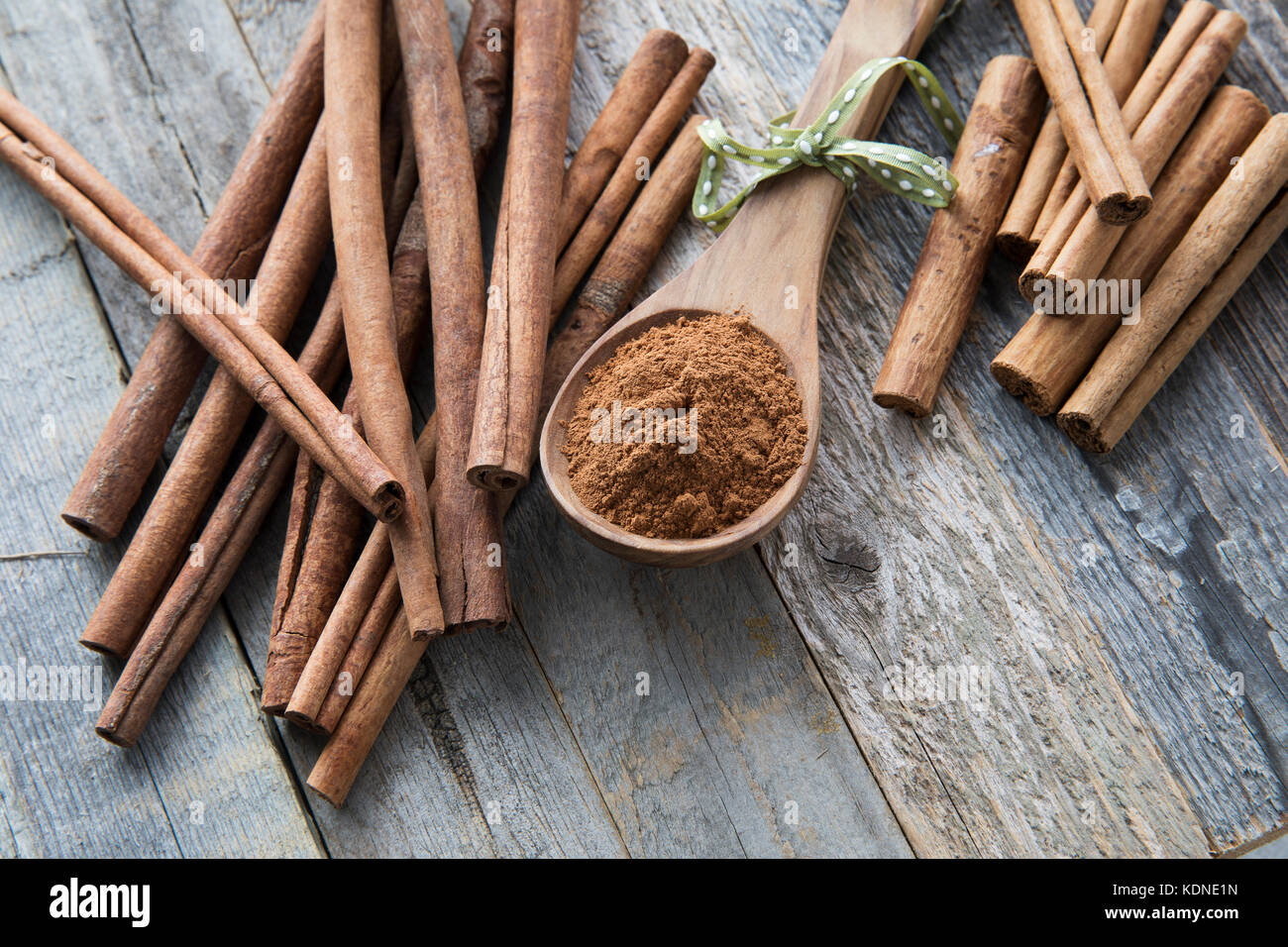 Wooden spoon filled with ground cinnamon and surrounded by cinnamon ...