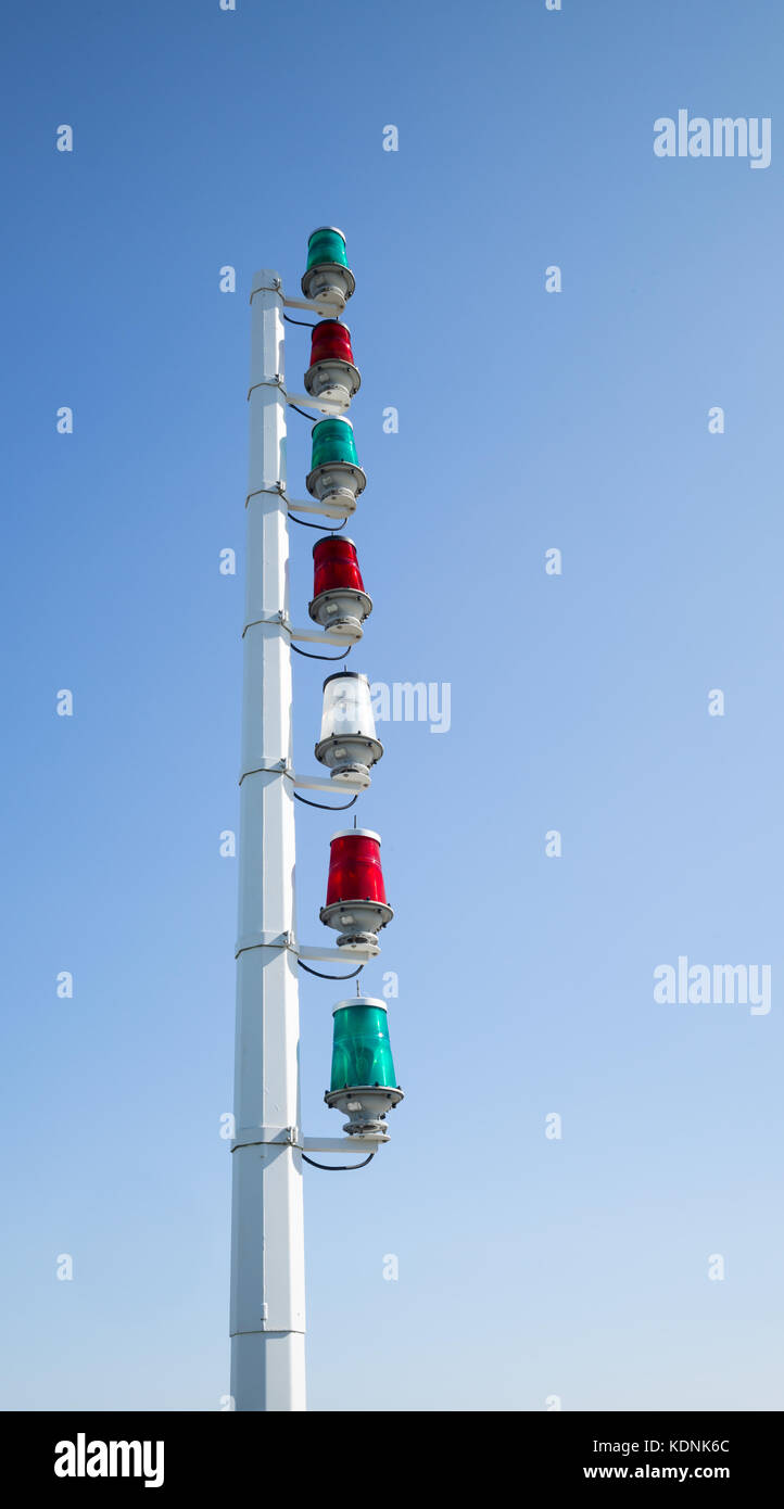 Red and green maritime signal lamps on metal column on harbour pier ...