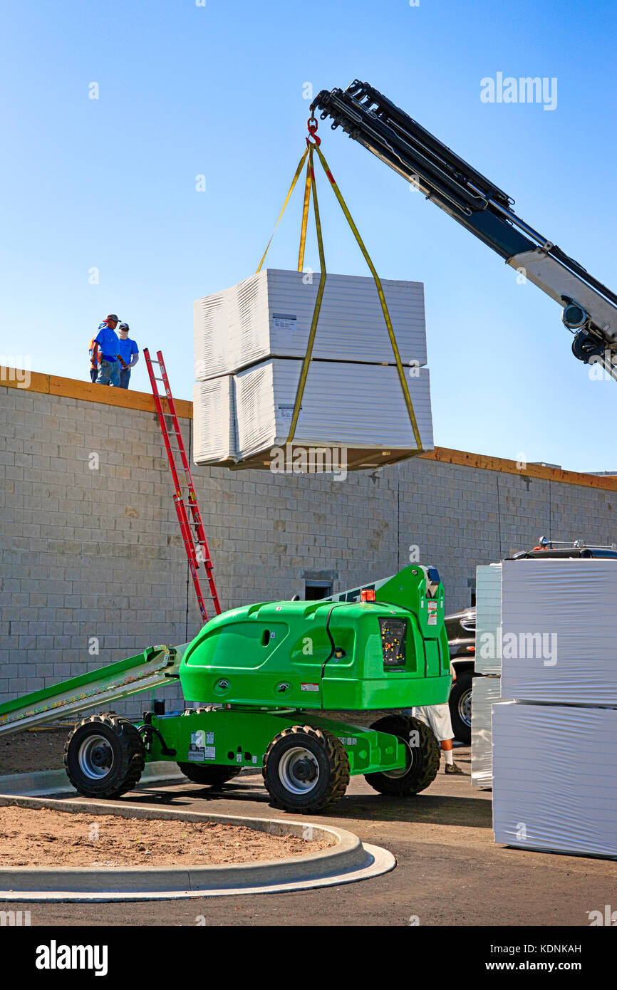 Mobile crane lifting polystryrene insulation tile pallets onto a roof ...