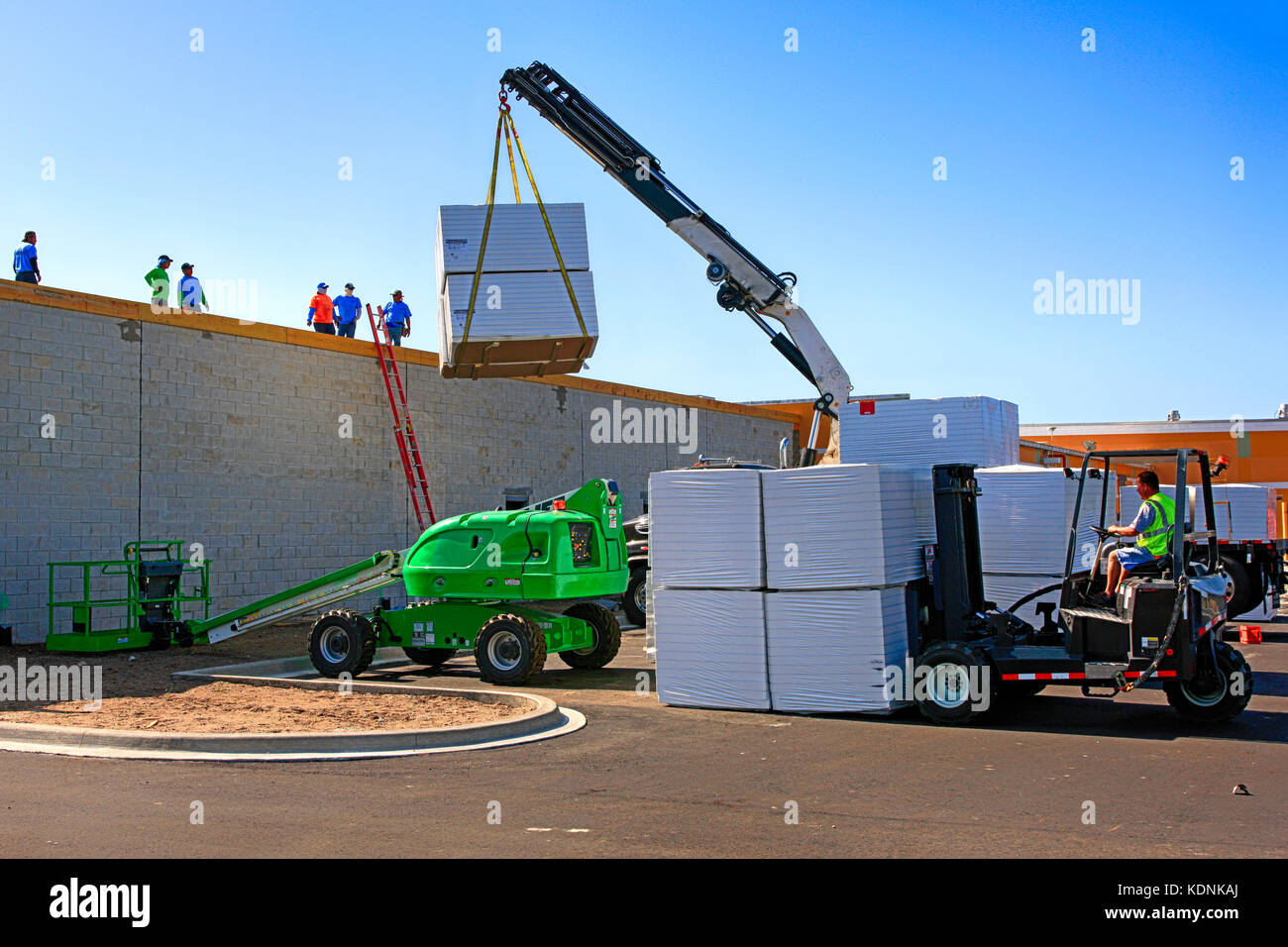 Mobile crane lifting polystryrene insulation tile pallets onto a roof ...