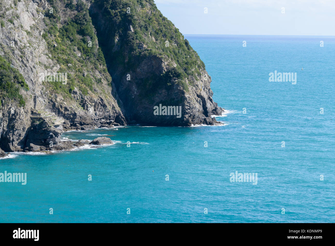 mountain overhanging the sea, with walls rich in vegetation, blue sea ...