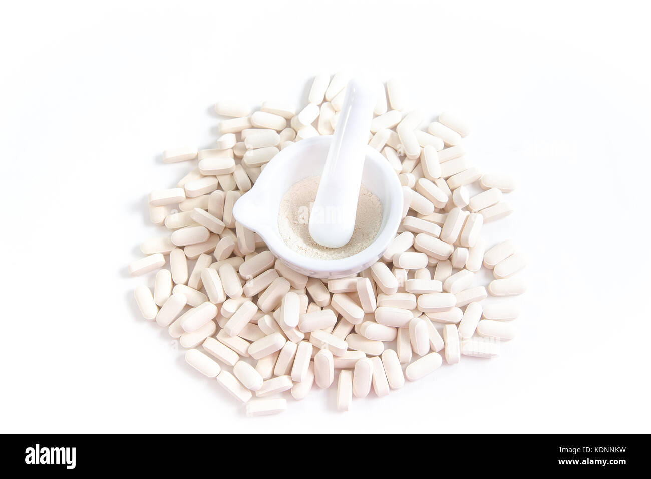 Circular of off-white tablets with a mortar and pestle on white ...