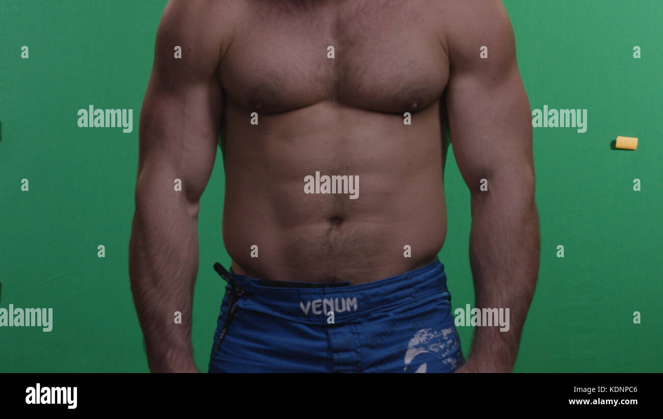 Muscular man standing on green screen Stock Photo - Alamy