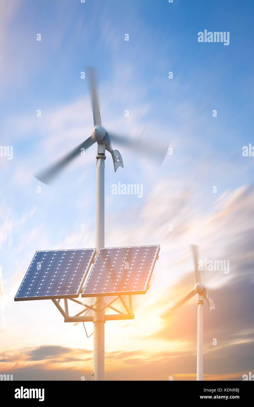 solar panels and wind turbines against city on background under blue ...