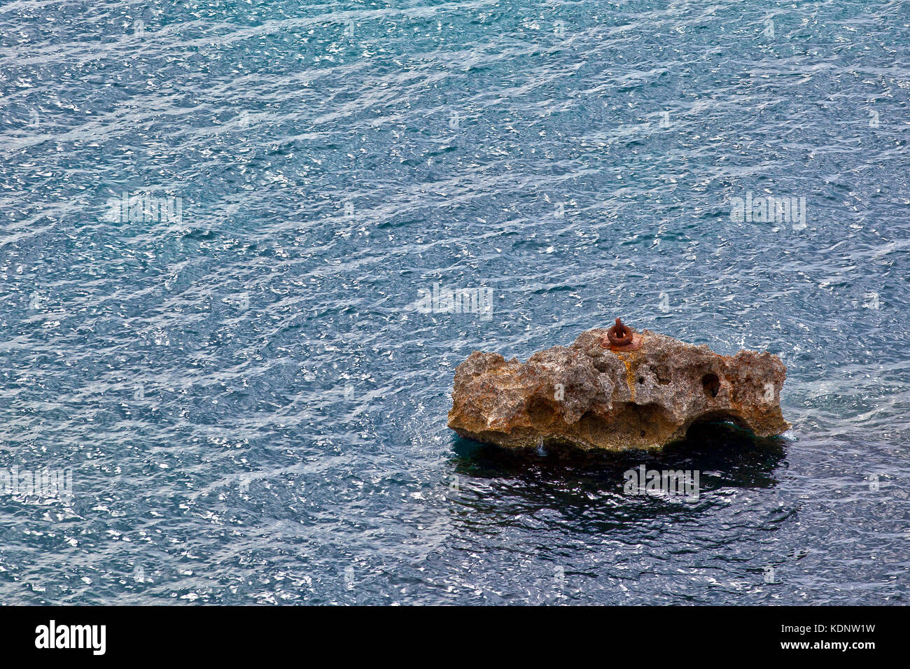 Jagged rock out at sea with textured ocean surface backdrop Stock Photo ...