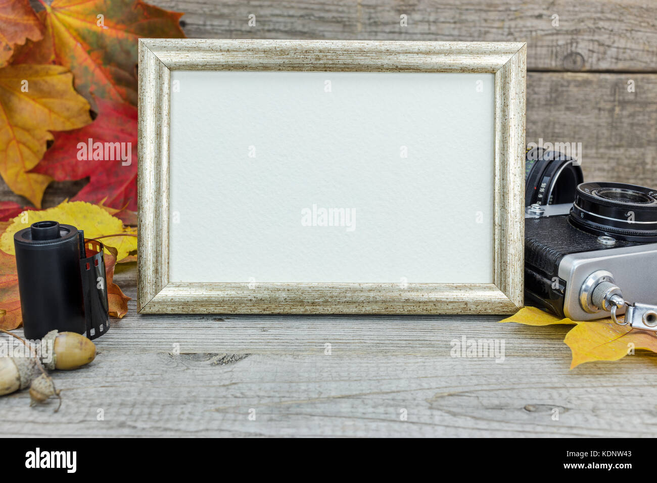 old camera, empty photo frame and film roll on grey wooden background ...
