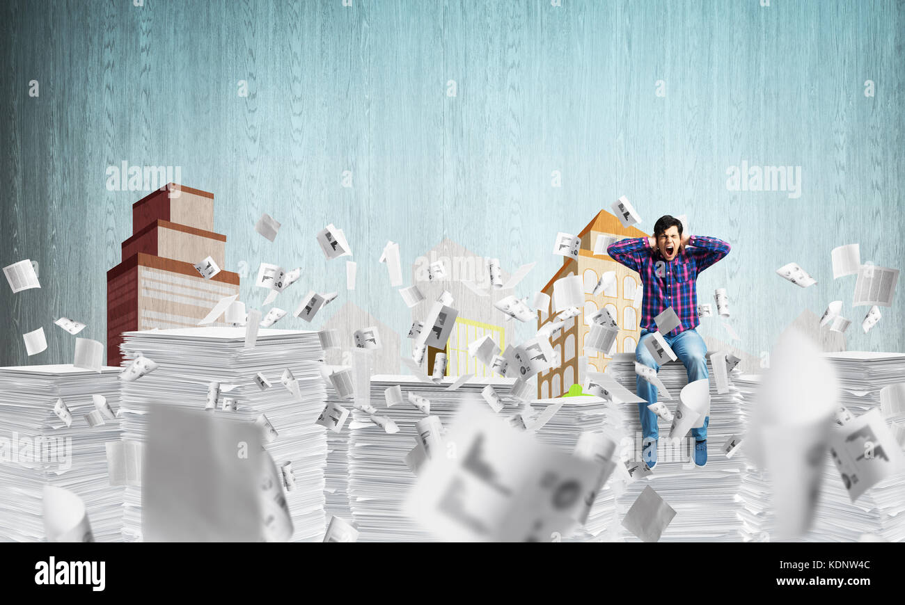 Young man sitting on pile of paper documents Stock Photo - Alamy
