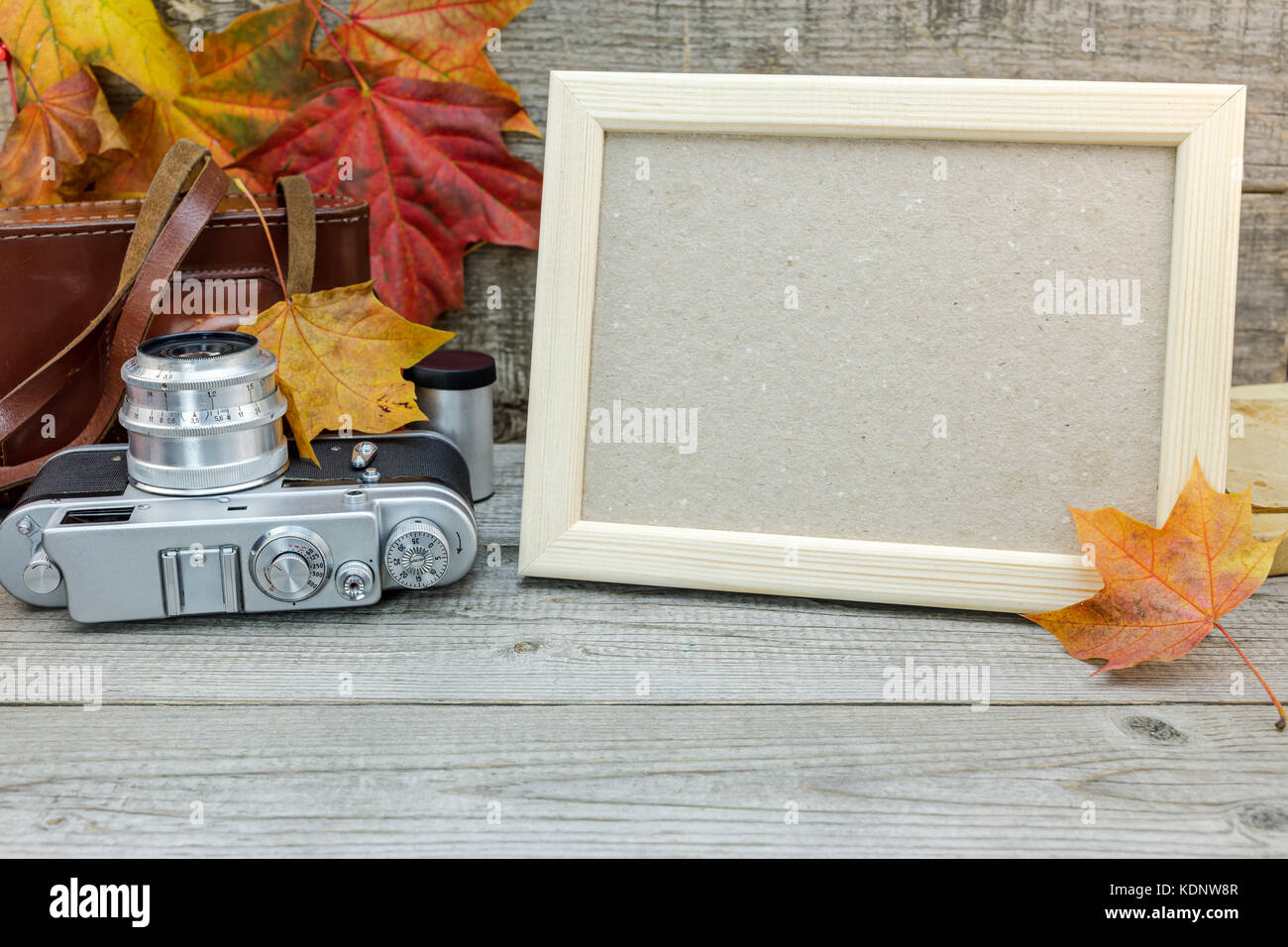 empty photo frame and vintage camera on grey wooden desk with vibrant ...