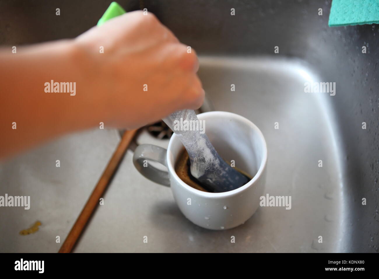 Grey mug with hand in metal washing up sink Stock Photo - Alamy
