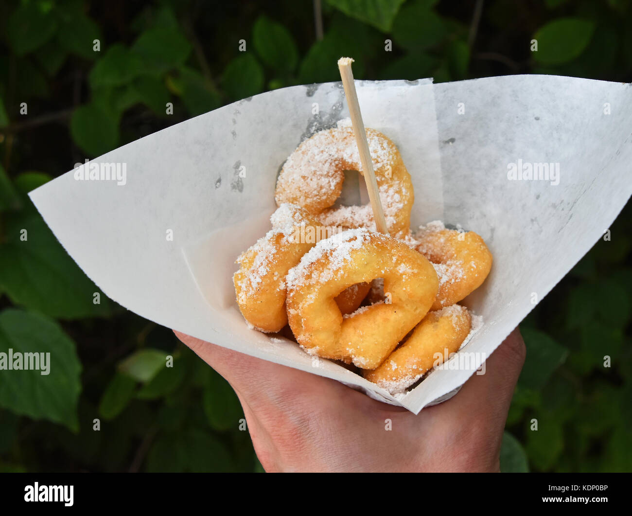 Woman hand holding portion of fresh small mini ring donuts with sugar ...