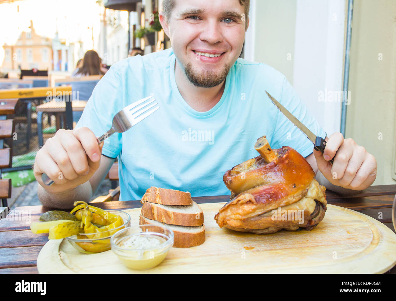 man eating knuckle of pork and drinks beer Stock Photo - Alamy