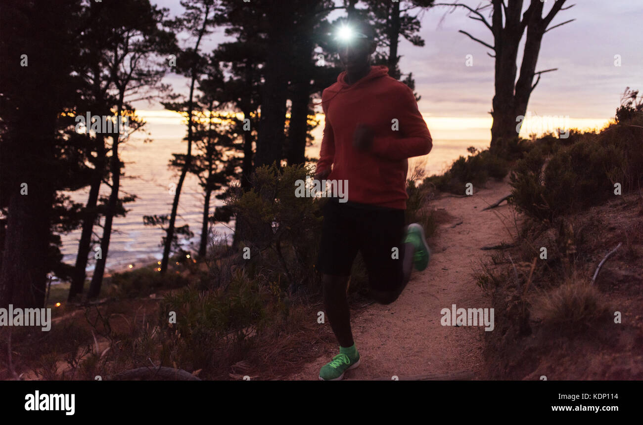 Young African man wearing a headlamp jogging at dusk Stock Photo - Alamy