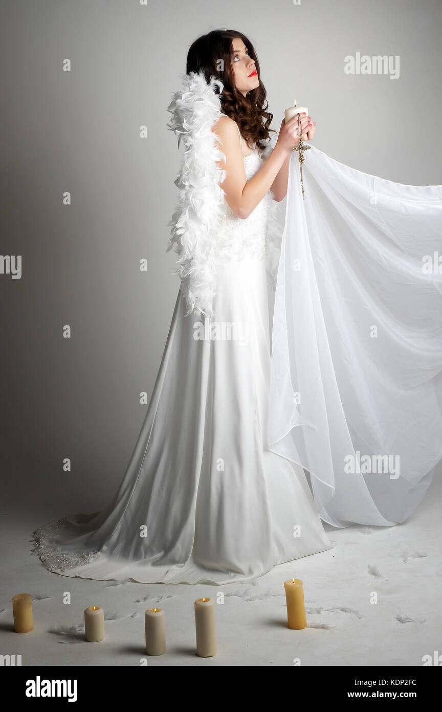 Sweet girl with a beautiful face in the form of an angel posing on gray ...