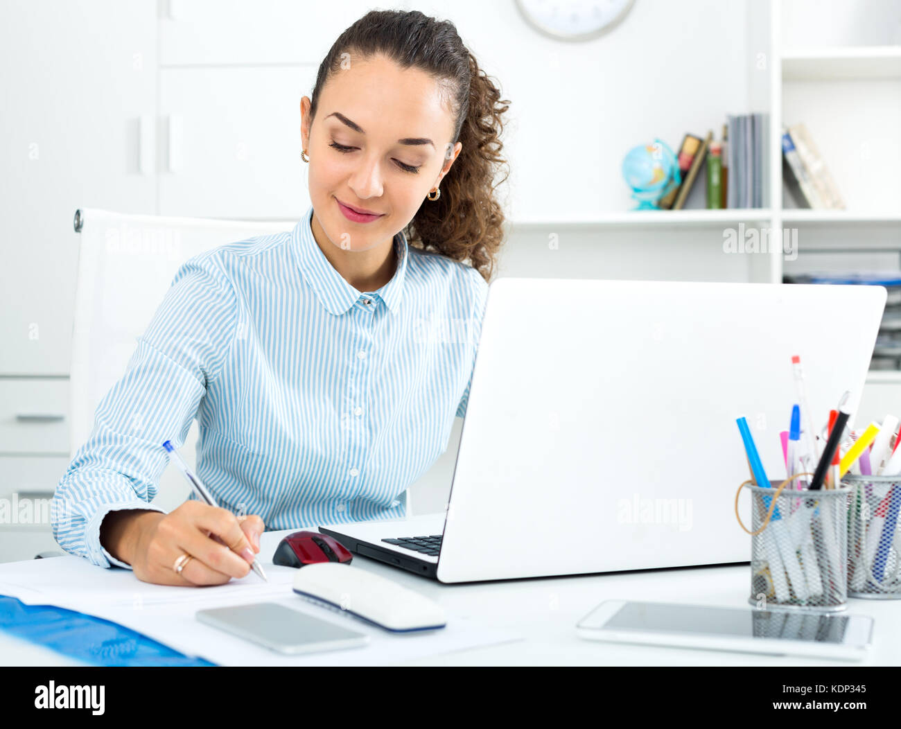Pretty business lady sitting at office desk with laptop Stock Photo - Alamy