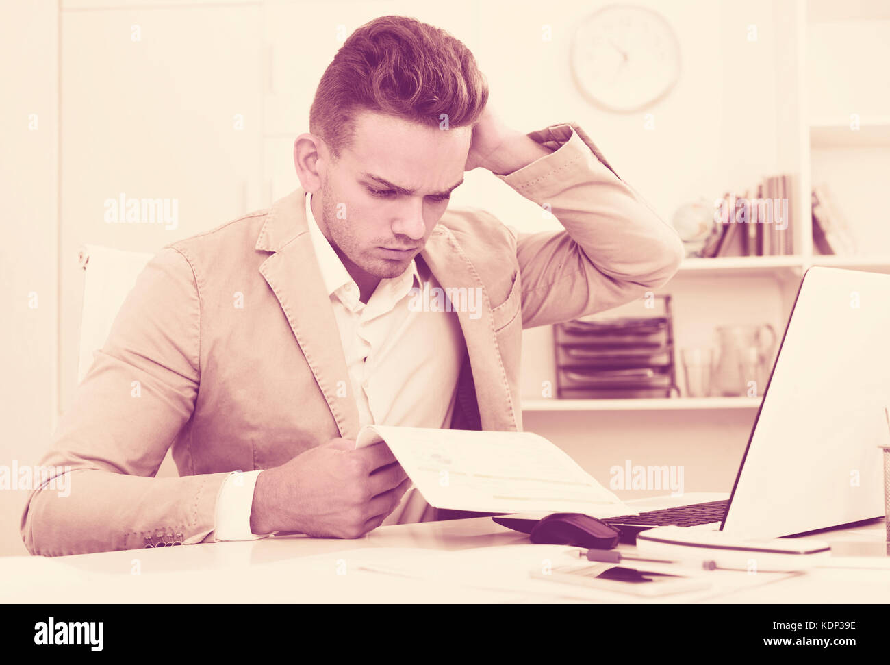 Sad young man having business problems with documents at workplace ...