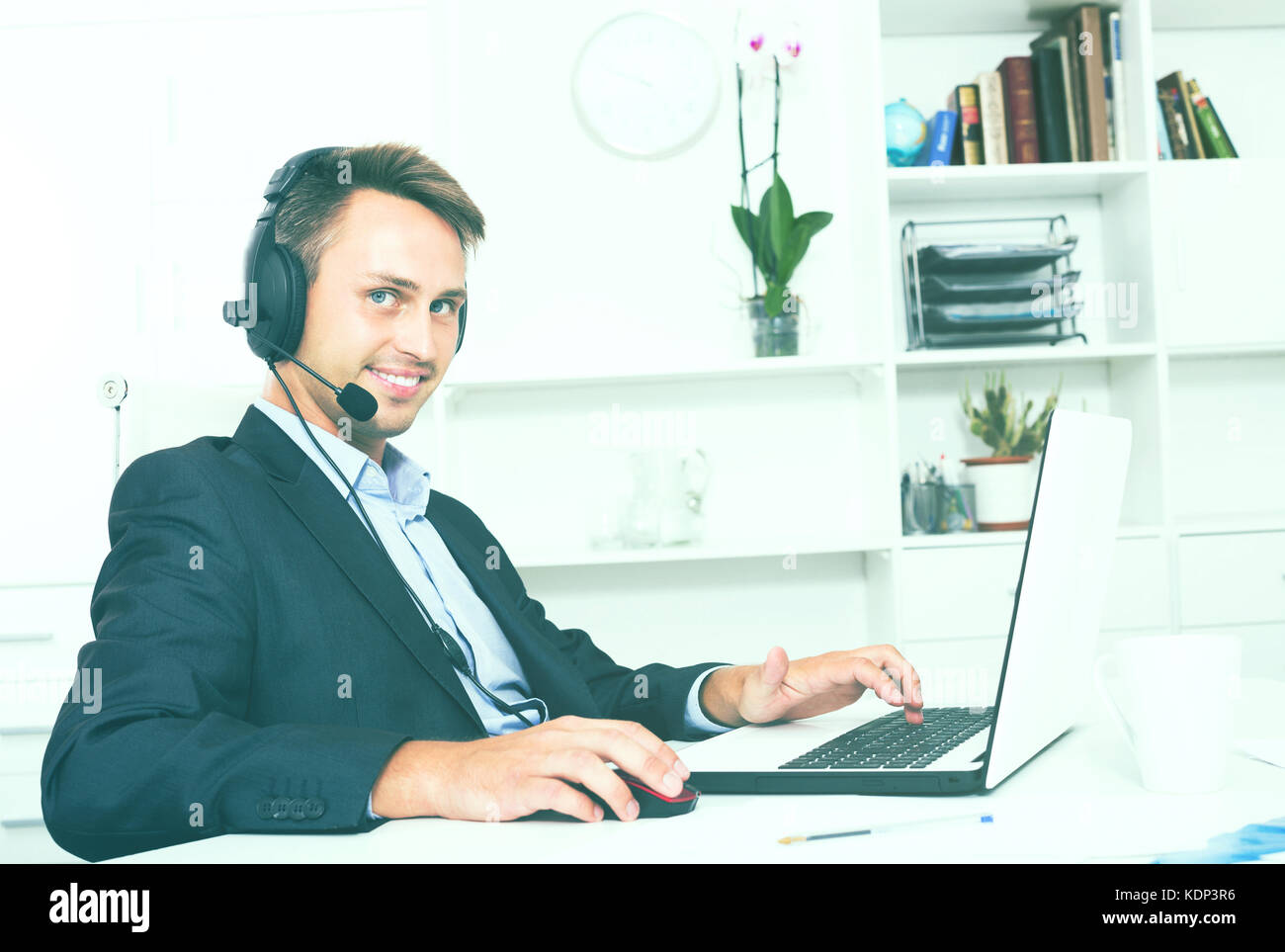 Young smiling male operator with headset on answering at call center ...