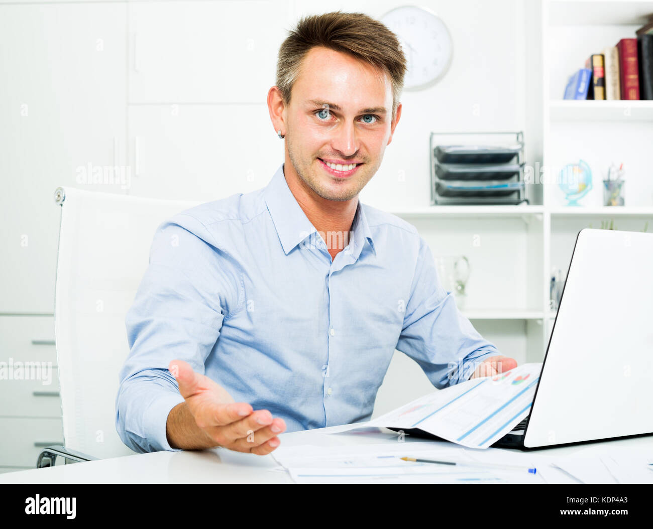 Cheerful professional man sitting with laptop and having paper document ...
