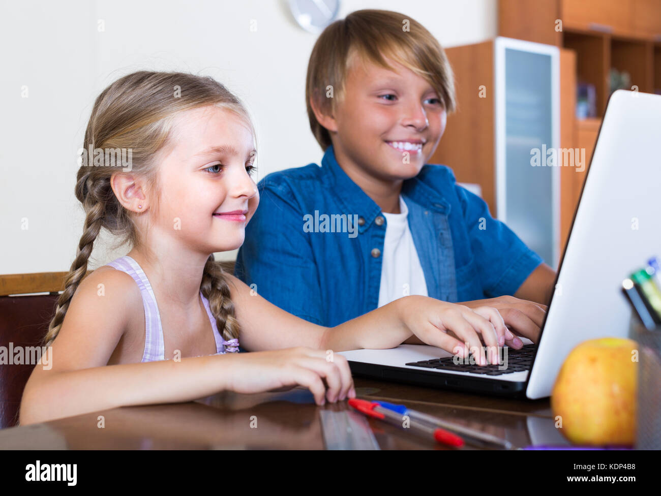 Happy children playing game online on laptop at home. Focus on girl ...