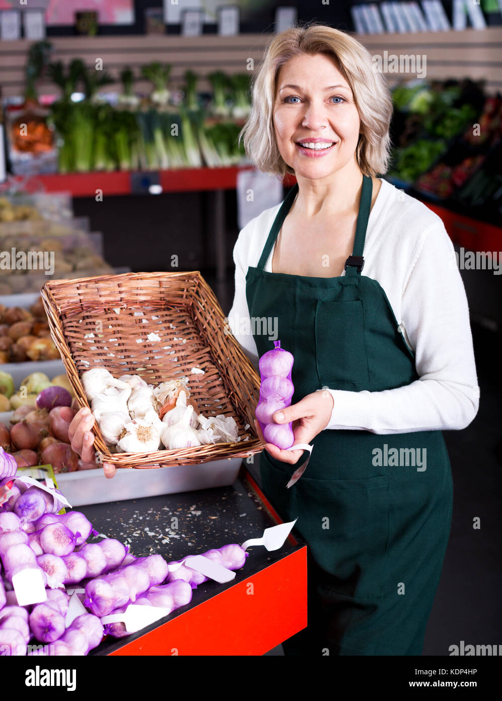 Portrait of mature woman selling garlic in grocery and smiling Stock ...
