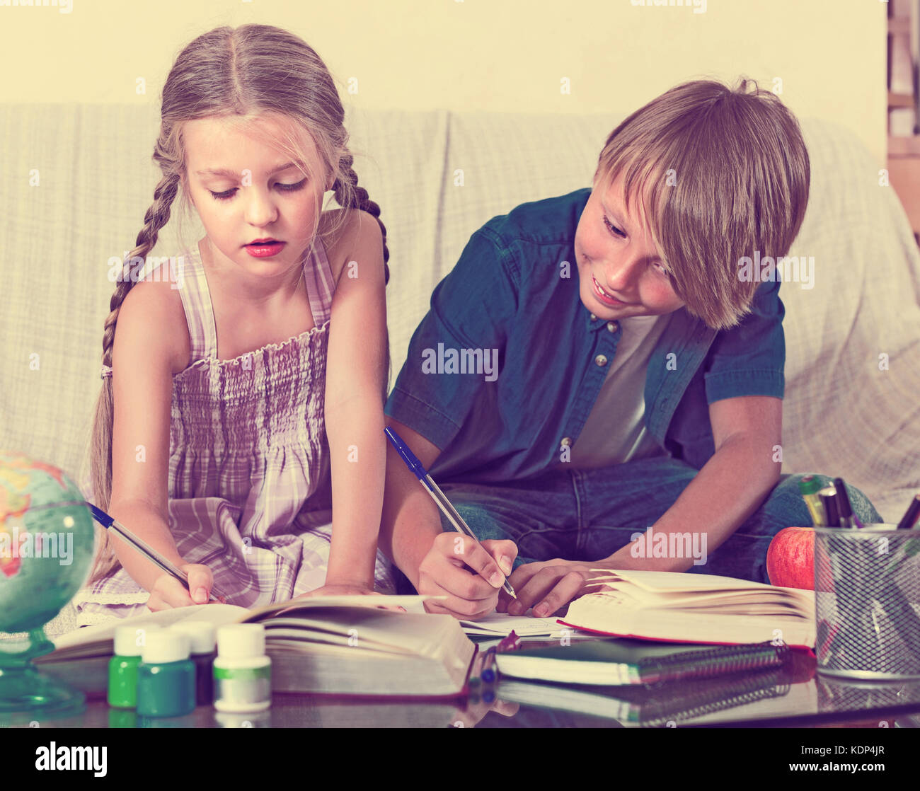 Smiling boy and cute little girl doing homework together Stock Photo ...