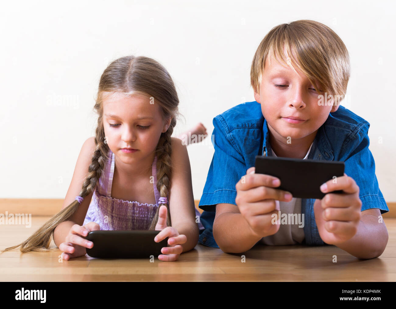 Portrait of happy kids playing with smartphones in domestic interior ...