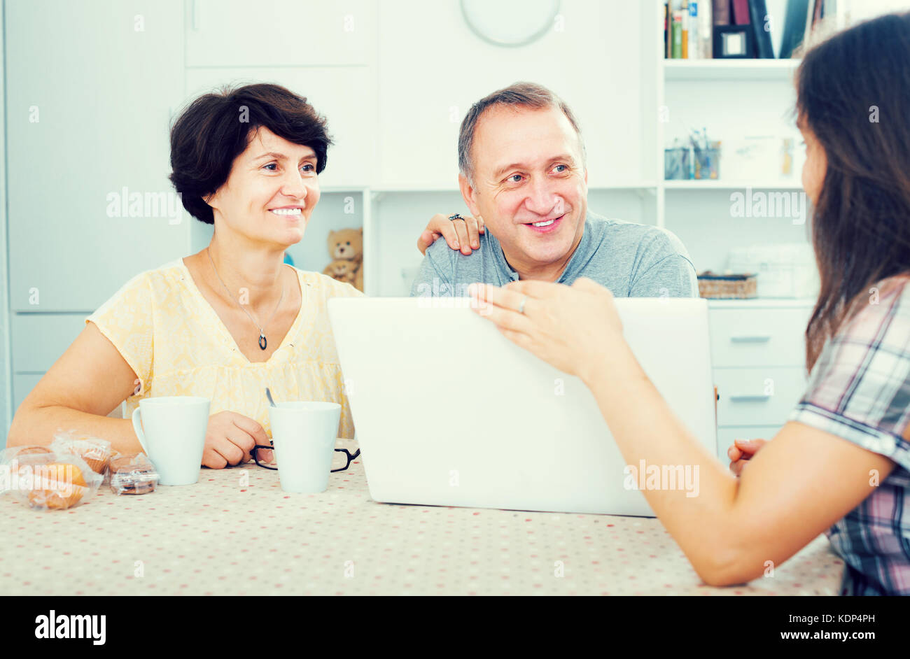 Adult daughter showing documents on laptop to her senior parents at ...