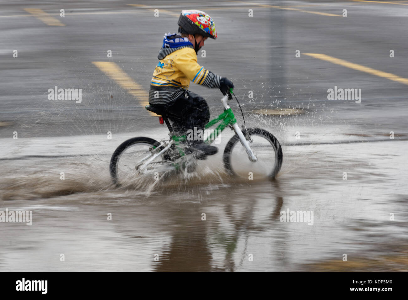 A little boy riding a bike through a big puddle Stock Photo - Alamy