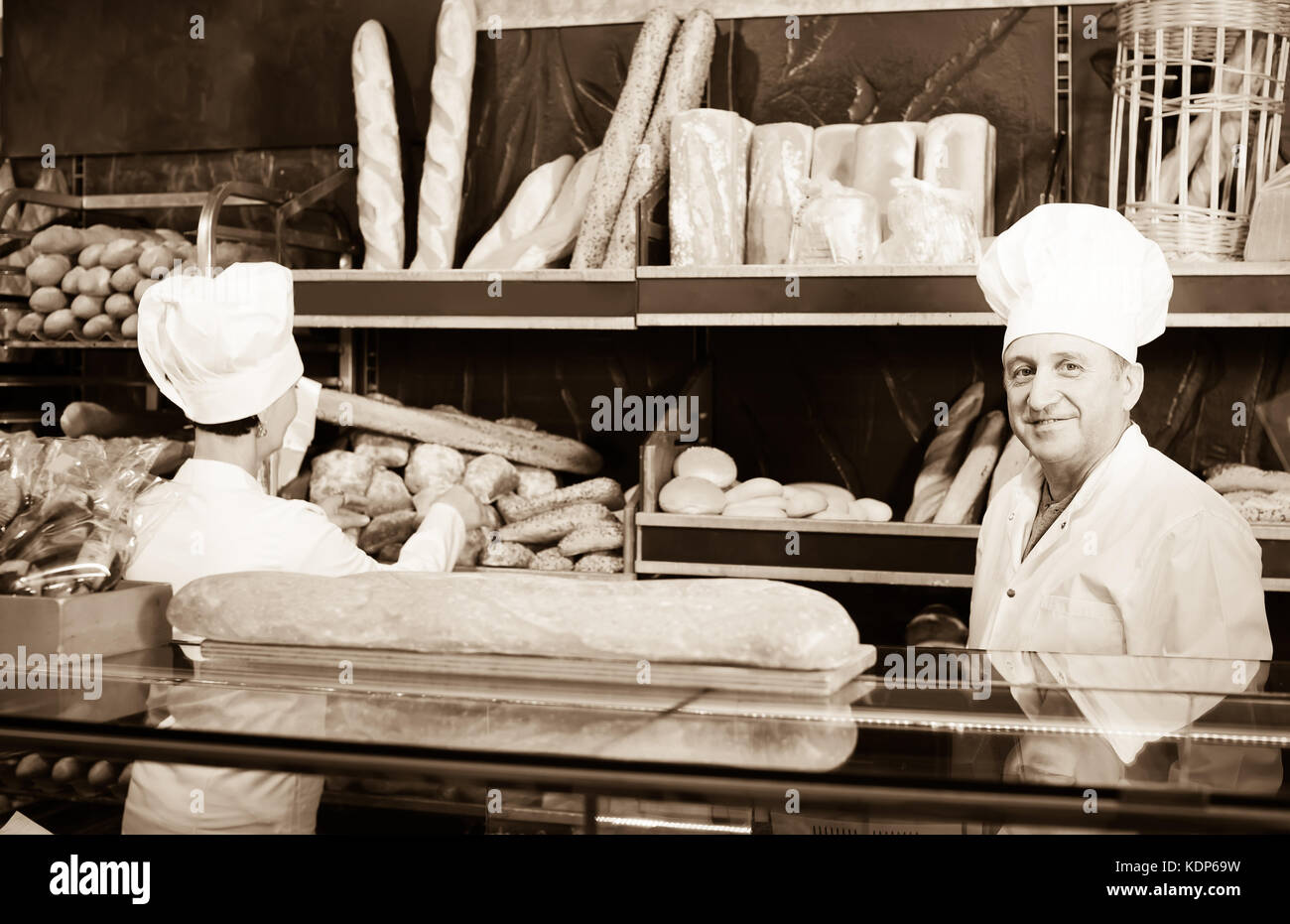 Bakery employees with tasty bread products on counter and shelves Stock ...