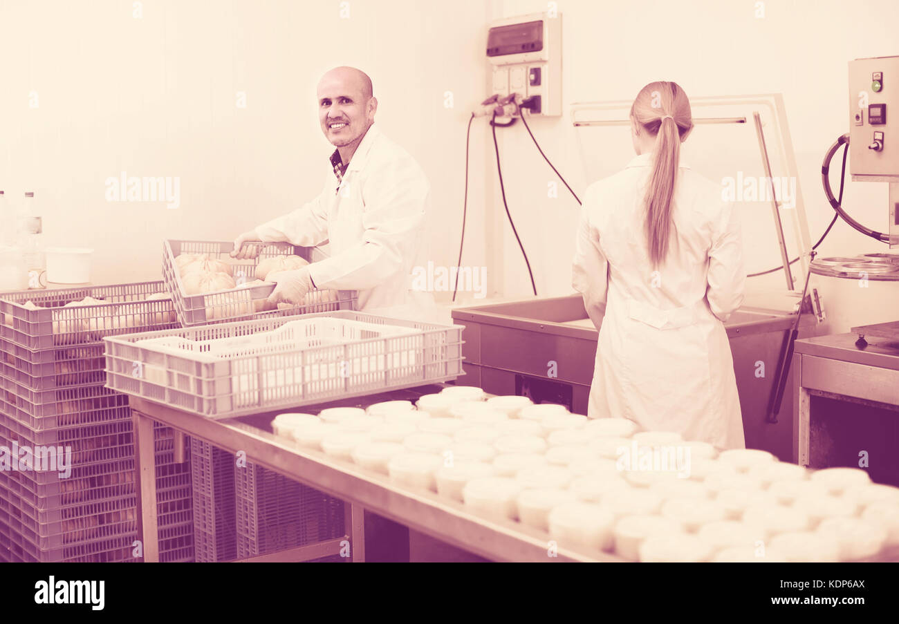 two workers in white coats working at cottage cheese production on ...