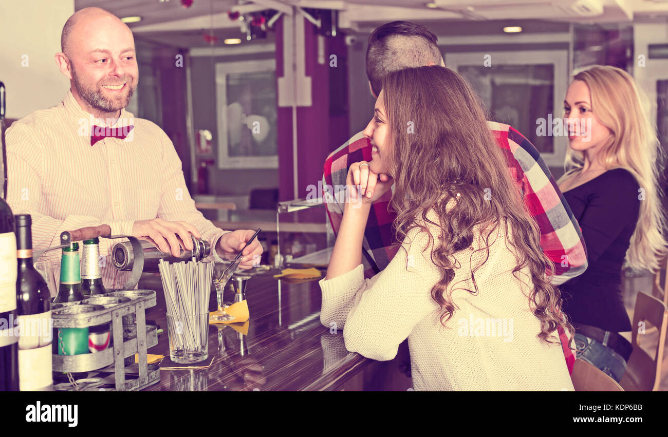 People having a party at a bar. Bartender is mixing drinks while an ...