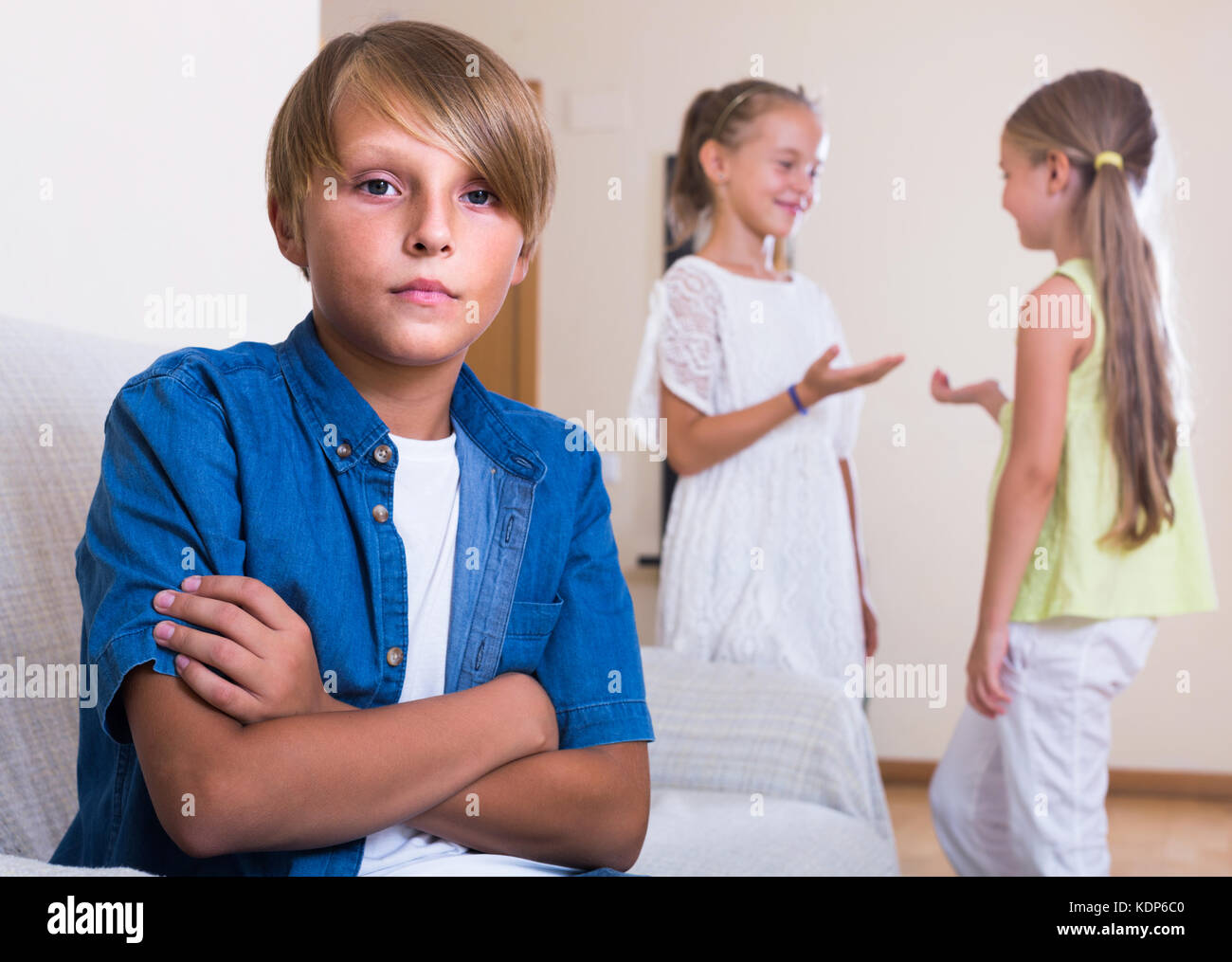 Two little european girls talking and sulky boy sitting separately at ...