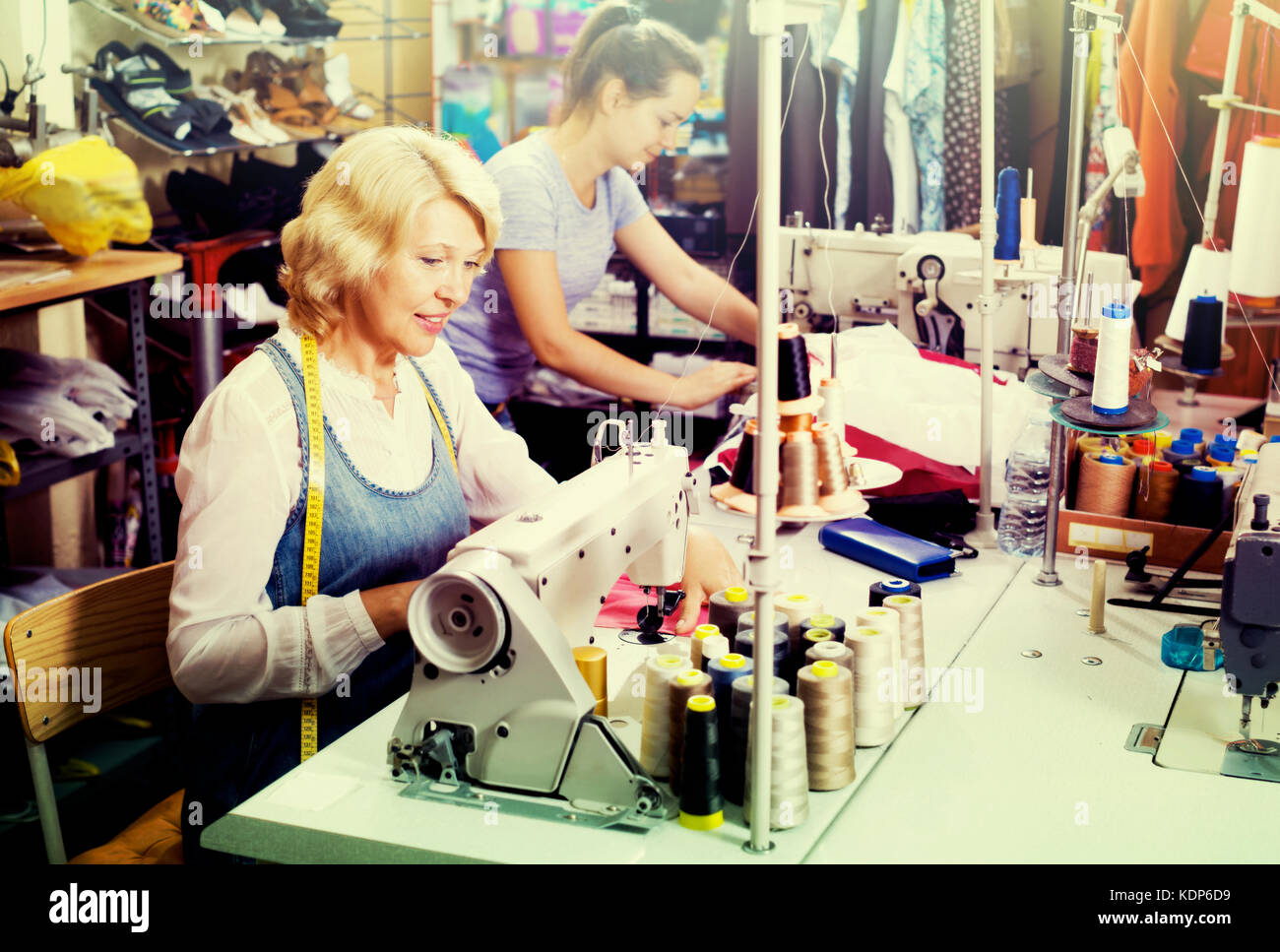 Two beautiful women sewing with professional equipment at atelier Stock ...