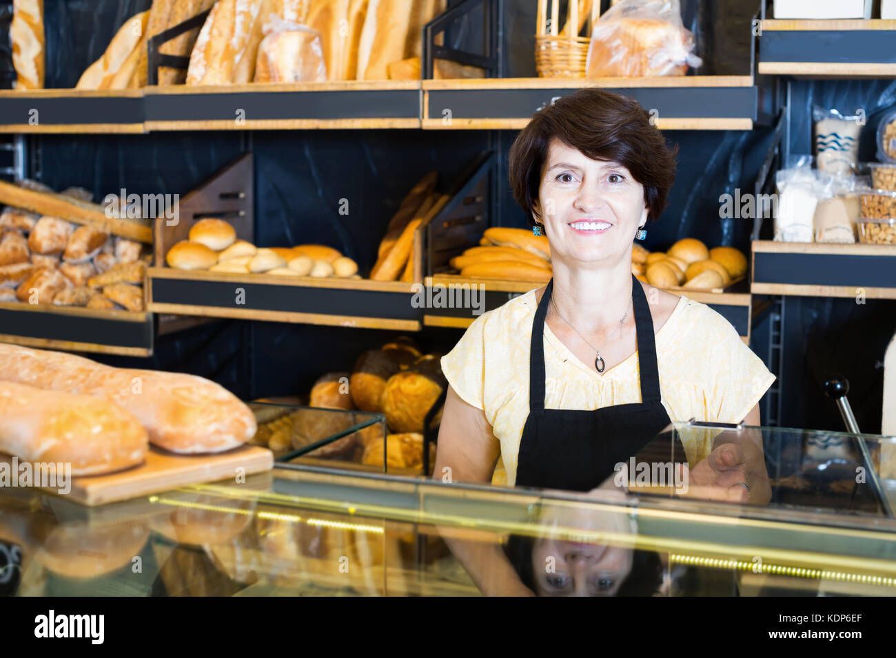 Middle aged woman baker with tasty bread products on counter Stock ...