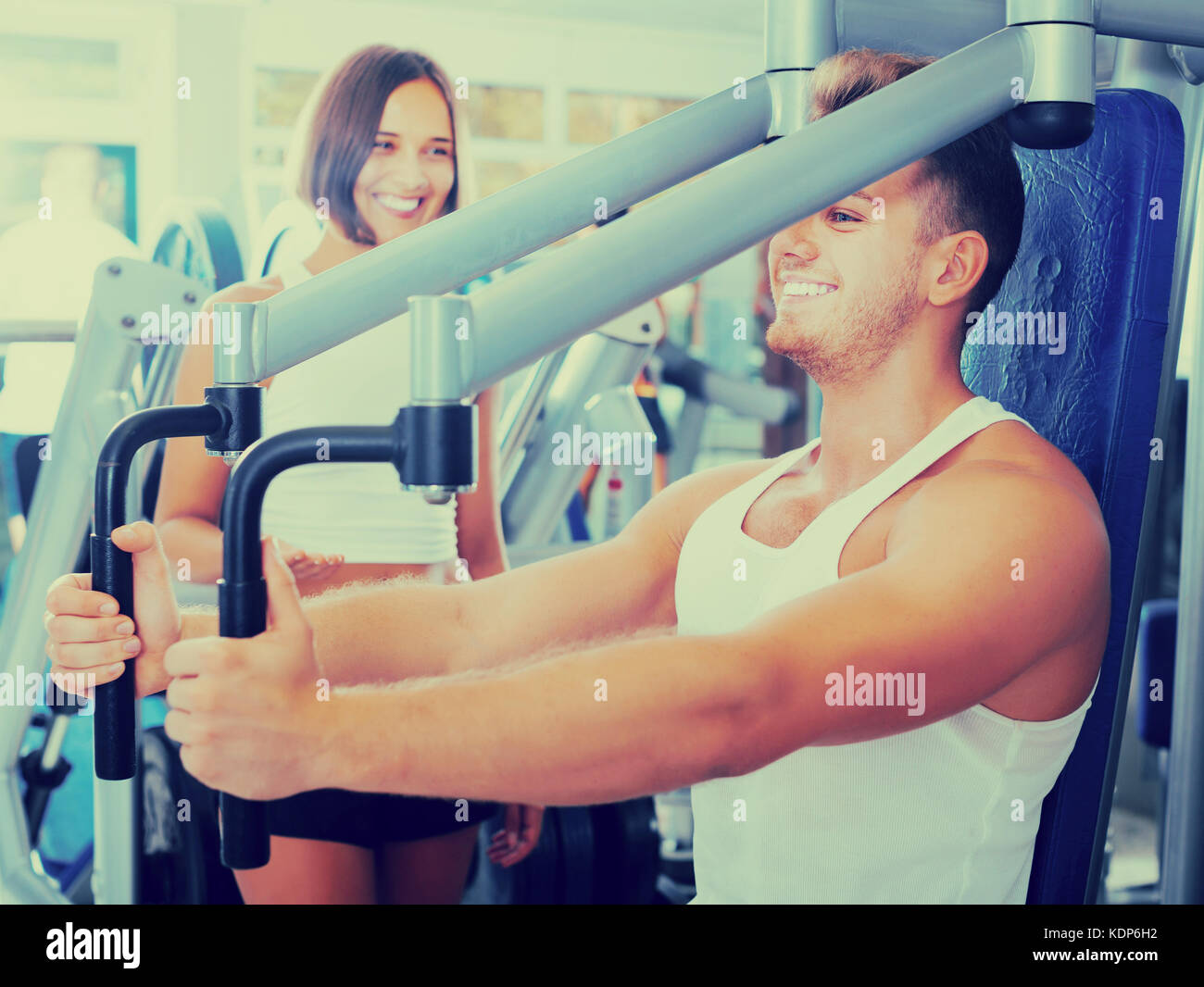 Young smiling female coach assisting man using fly machine in gym Stock ...