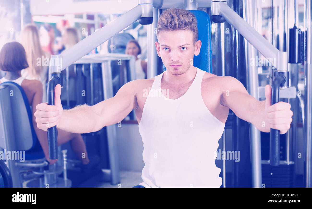 serious young man training upper body using fly machine in gym Stock ...