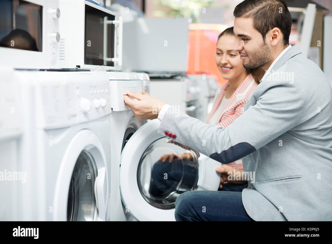 Young couple choosing washing machine at hypermarket and smiling Stock ...