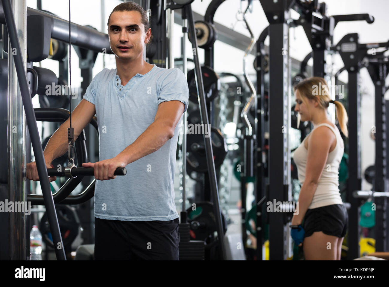 smiling adults having strength training under coach control in gym ...