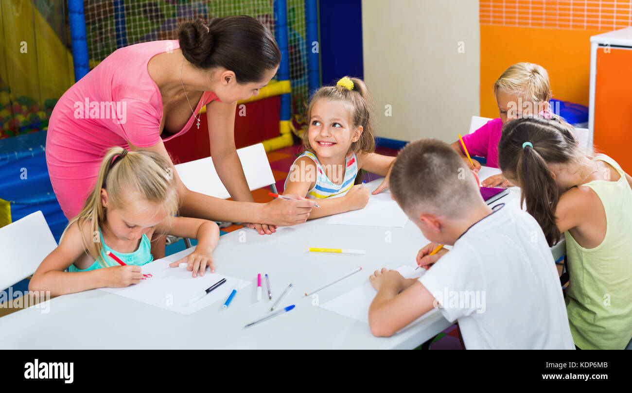 Smiling kids drawing together with tutor at hobby group indoors Stock ...