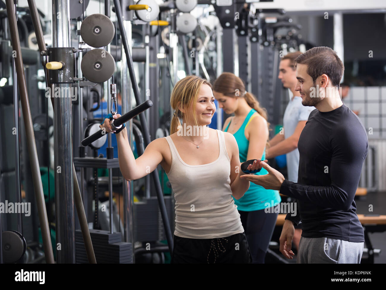 Happy smiling young people doing powerlifting on machines in gym Stock ...
