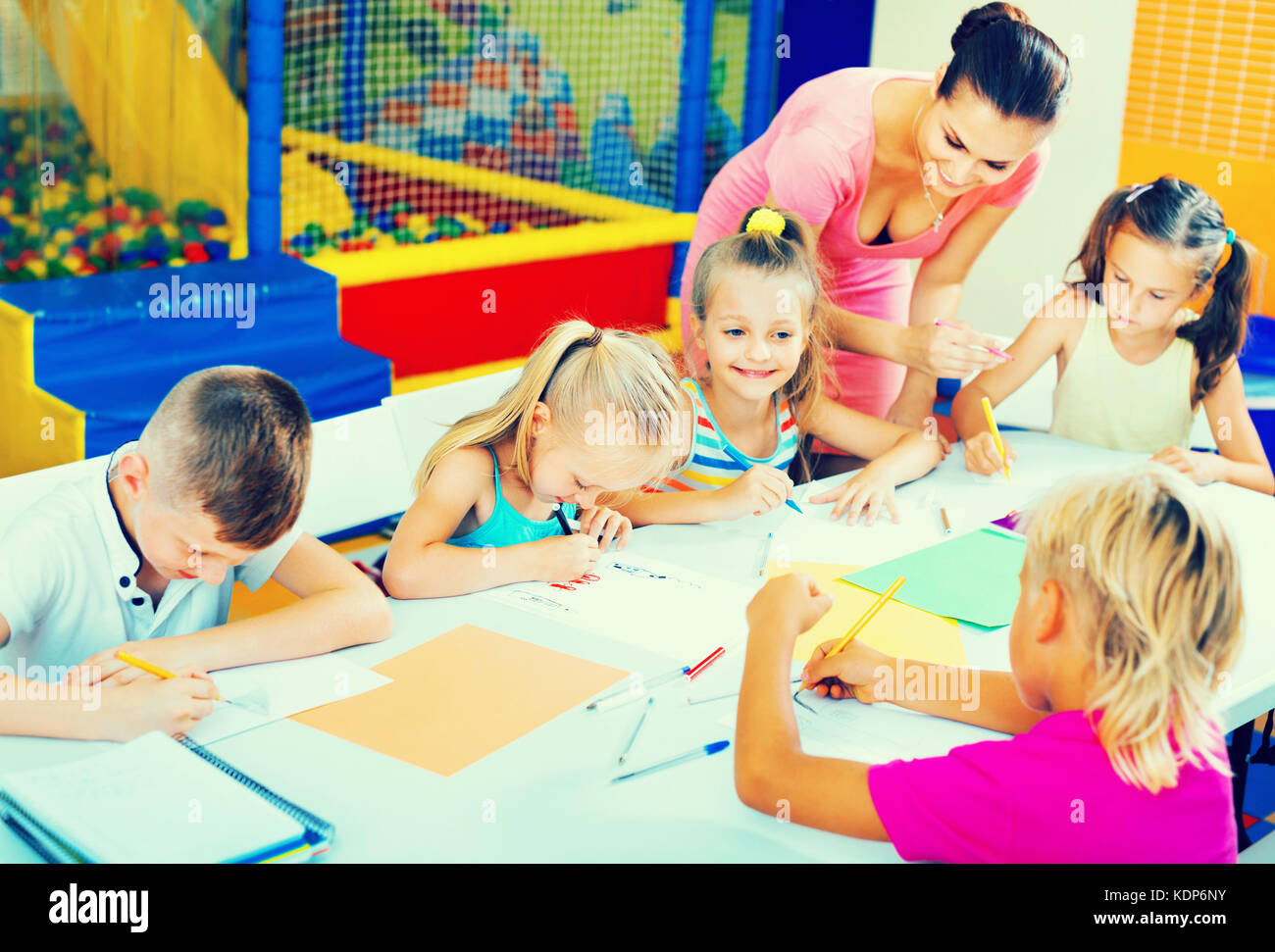 Smiling glad kids drawing together with tutor at hobby group indoors ...