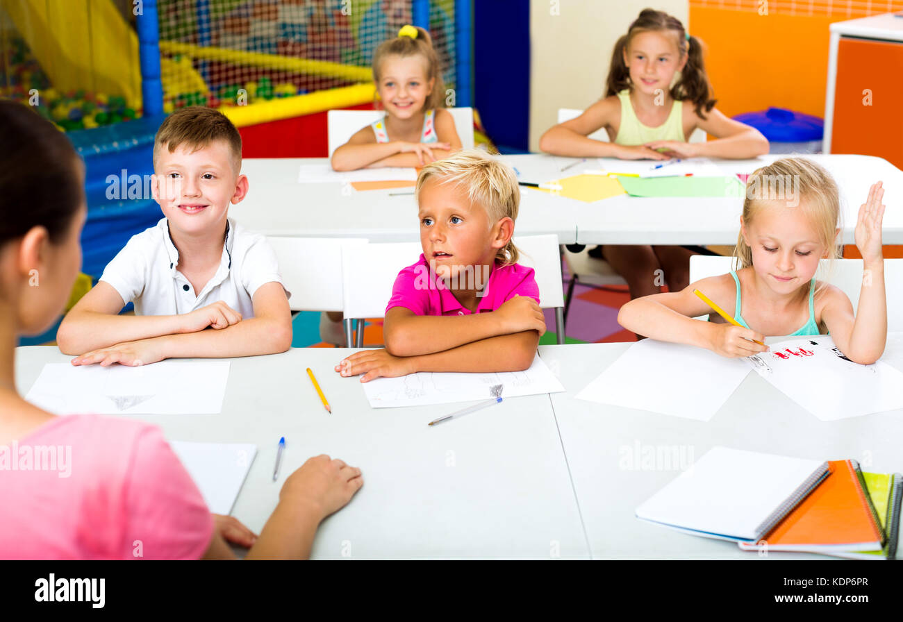 Attentive kids sitting and listening cheerful teacher in elementary ...
