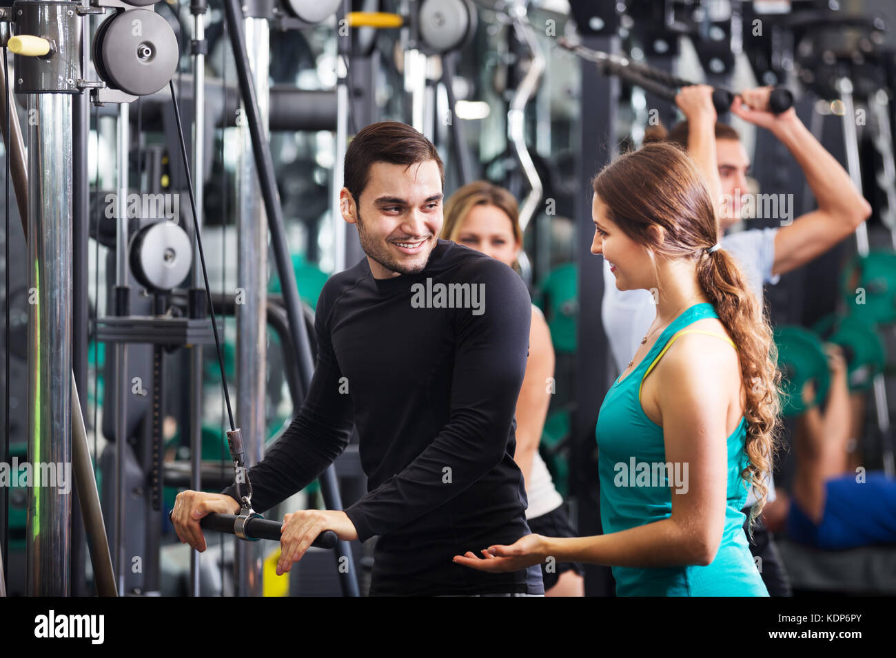 Young happy adults doing powerlifting on machines in fitness club Stock ...