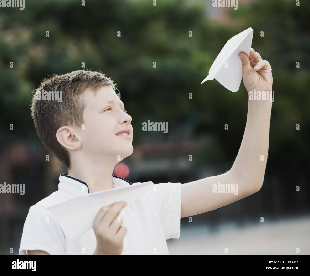 portrait of glad boy throwing paper airplanes in park on summer day ...