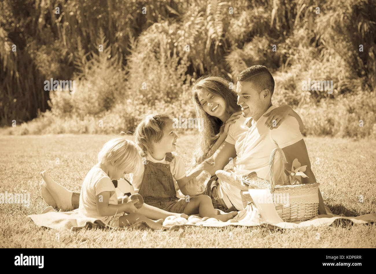 Young smiling parents with little daughters having holiday with picnic ...