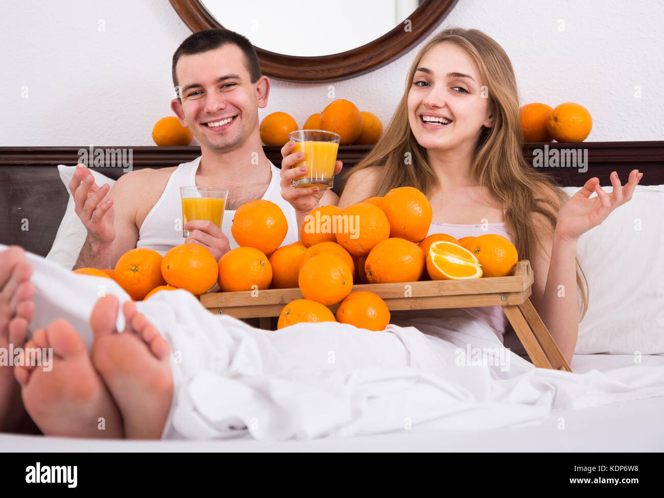 happy russian man and girlfriend drinking squeezed orange juice in bed ...