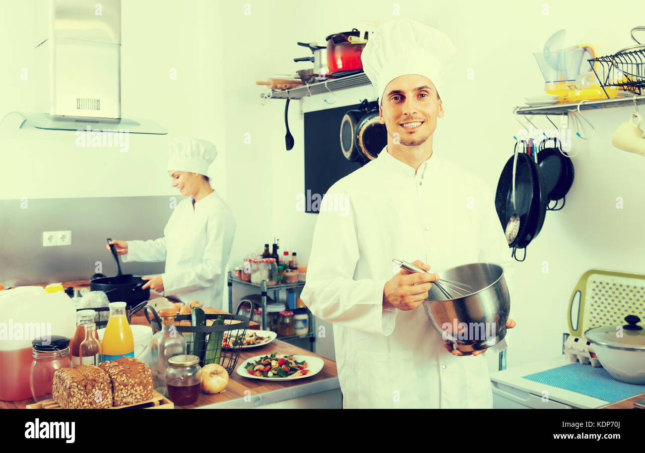 Smiling young man chef cooking food at restaurant's kitchen Stock Photo ...