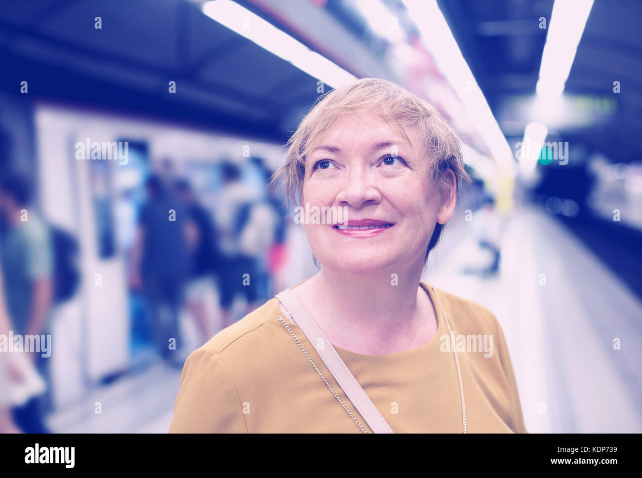 Positive senior woman commuter waiting train on public transport ...