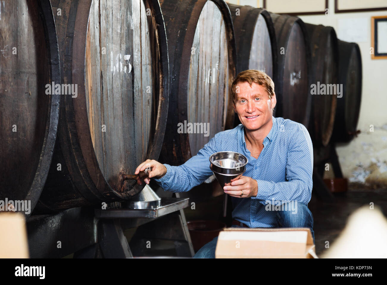 Portrait of male seller wearing uniform pouring liquor from wood to ...